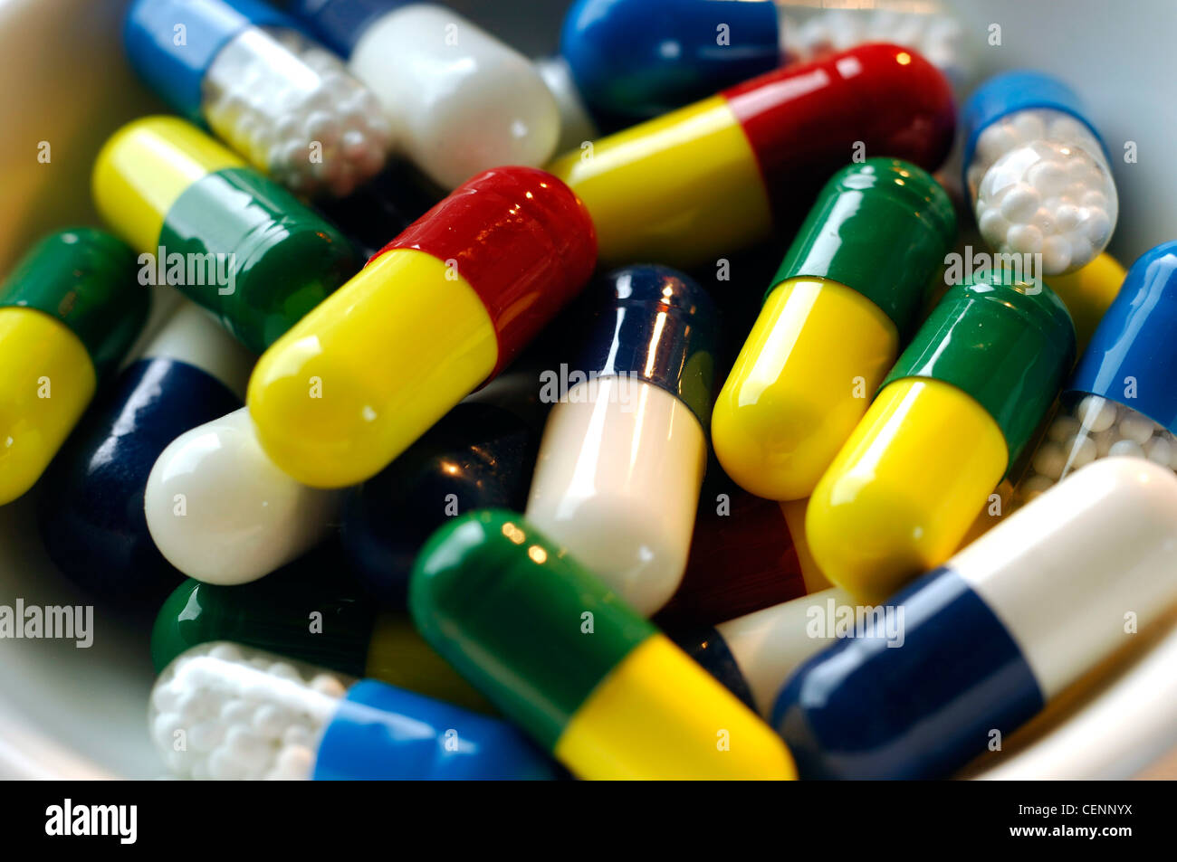 Assorted multicoloured capsules in a white bowl Stock Photo - Alamy