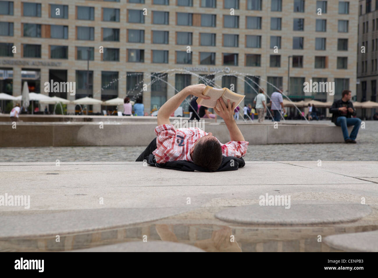 Man reading book leaning backwards outdoor Stock Photo - Alamy