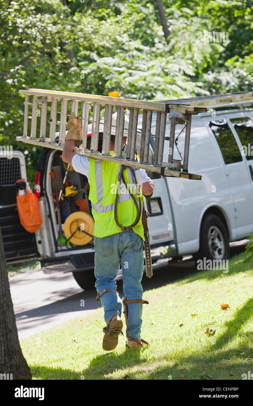 Lineman carrying a ladder back to his truck Stock Photo - Alamy