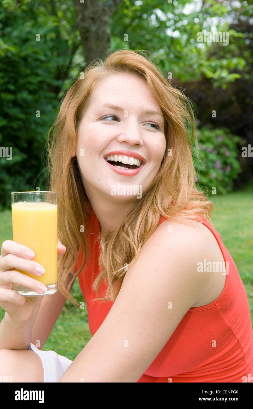 Female with light brown hair wearing a red vest, holding a glass of ...
