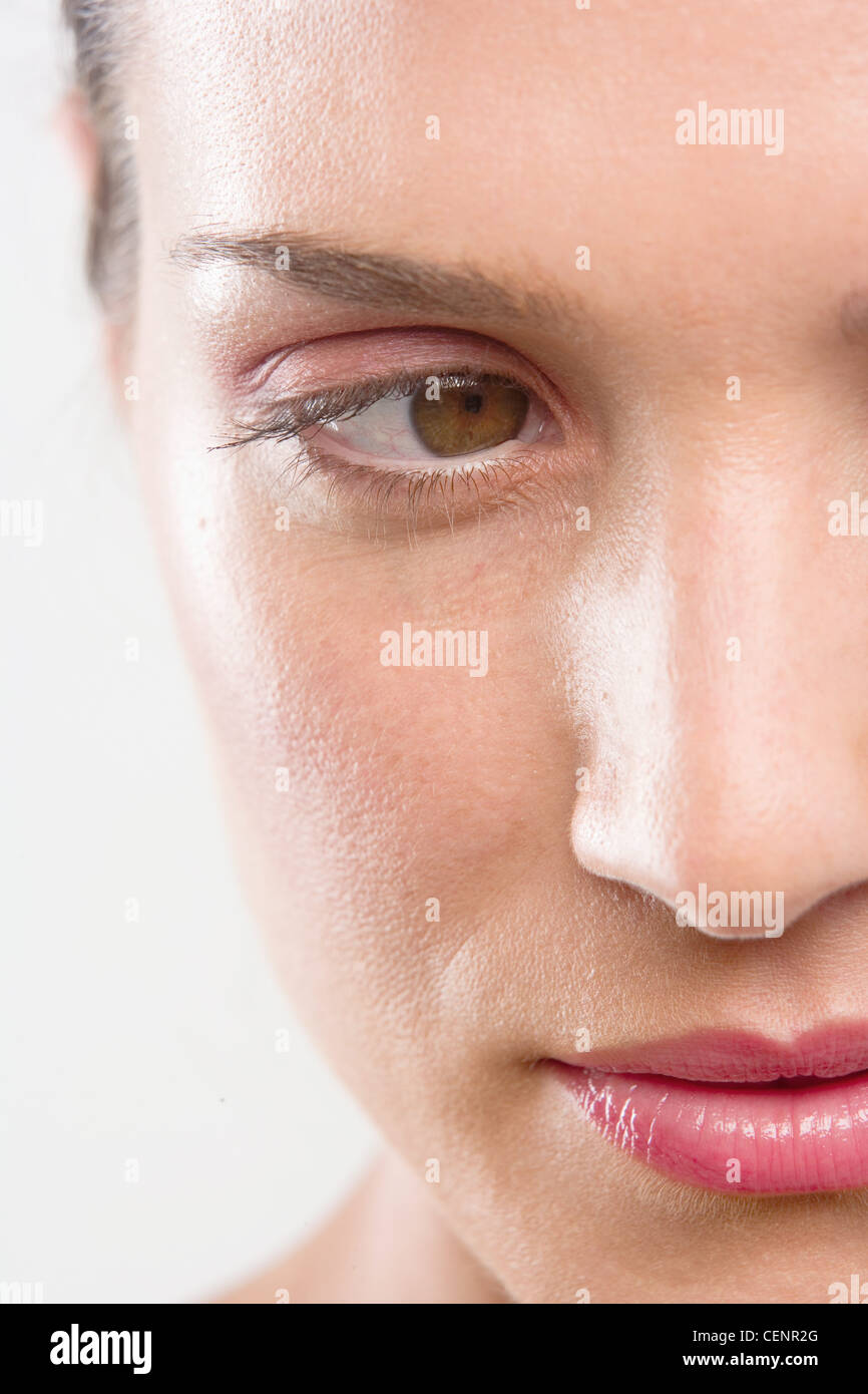 Close up half face of female with brunette hair off face wearing pink ...