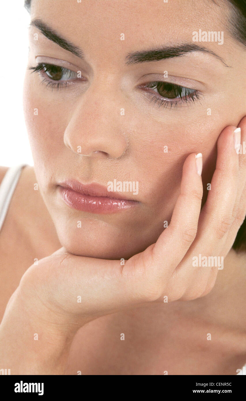 Female with brunette hair leaning chin in hand finger tips on cheek ...