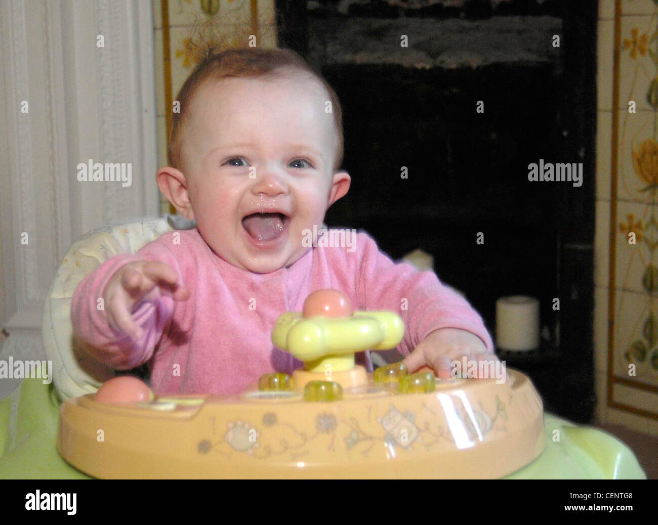 Female baby, wearing a pink babygro, sitting in baby walker, smiling ...