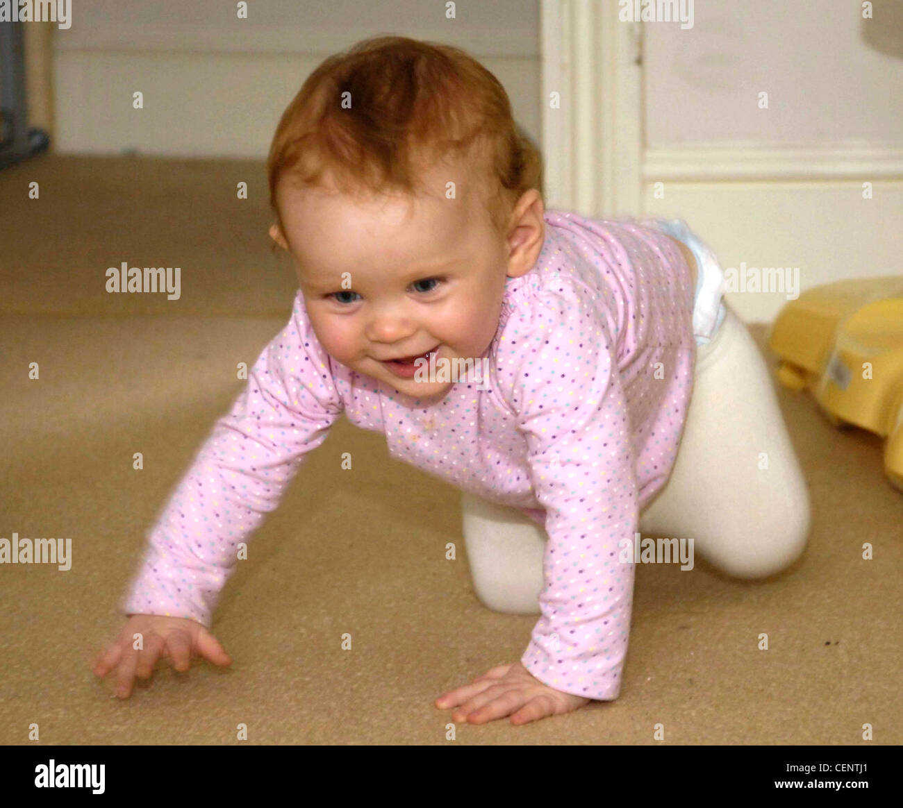 Female child crawling across carpet smiling Stock Photo - Alamy