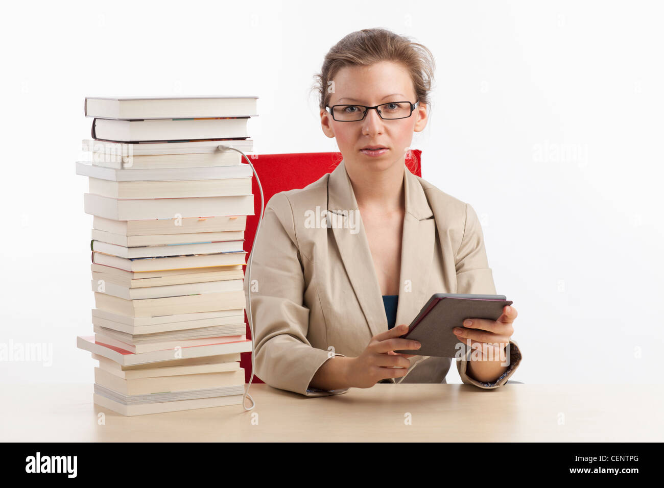 Businesswoman with ebook reader that is connected with a stack of books ...
