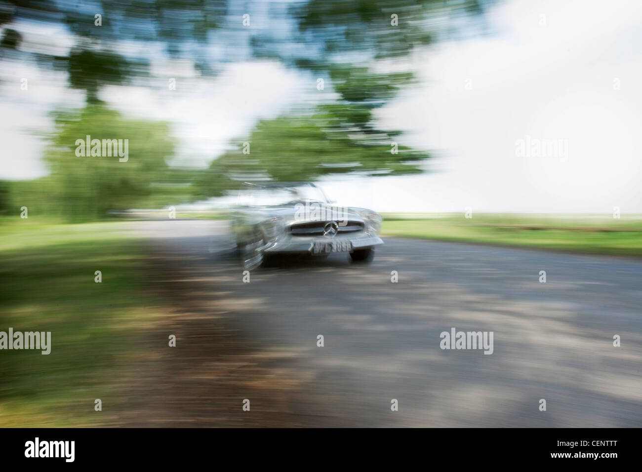 Blurred image of a man driving a silver convertible car Stock Photo - Alamy