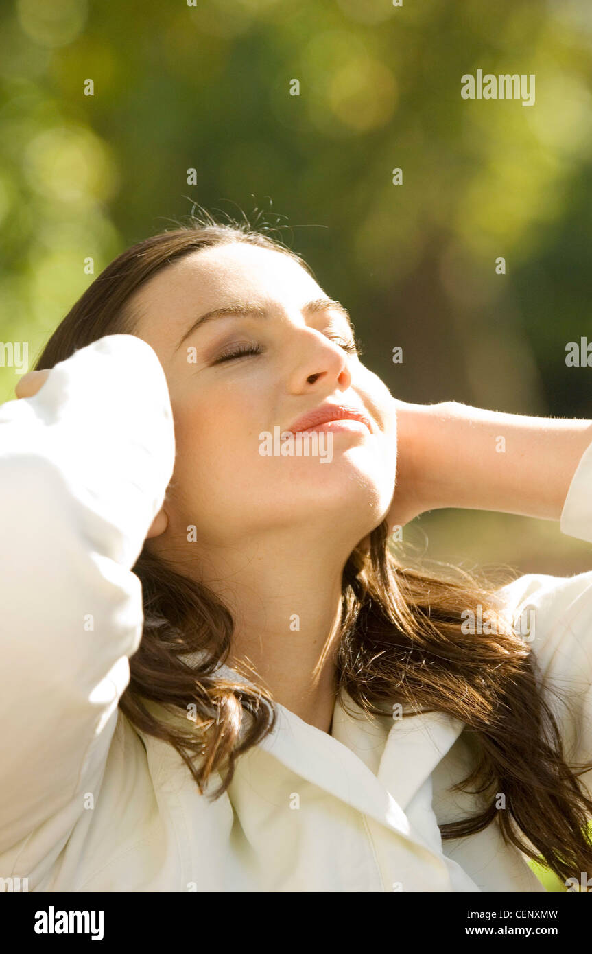 Female wearing cream jacket hands behind neck, head tipped back, eyes ...