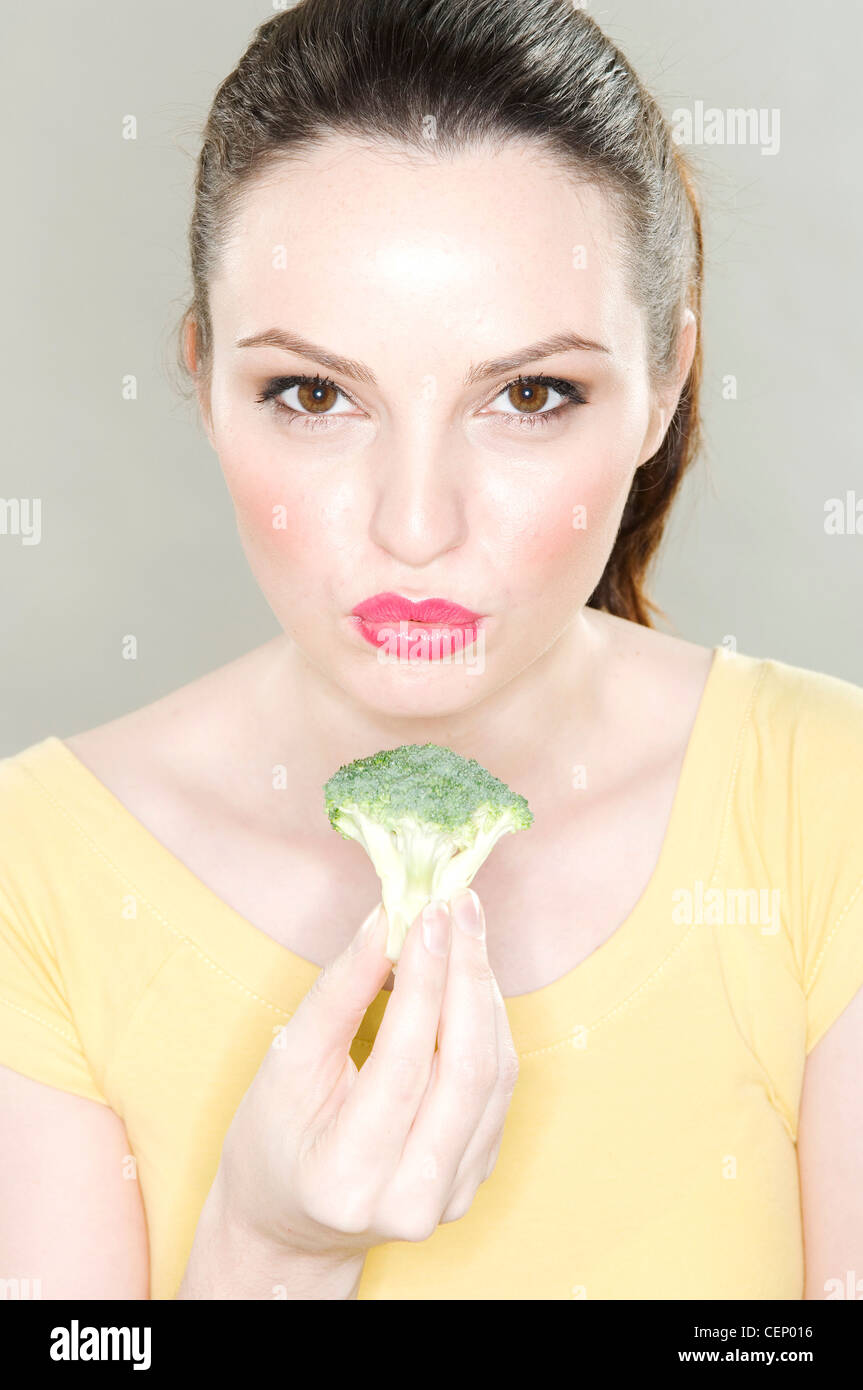 Female wearing yellow top eating broccoli Stock Photo - Alamy