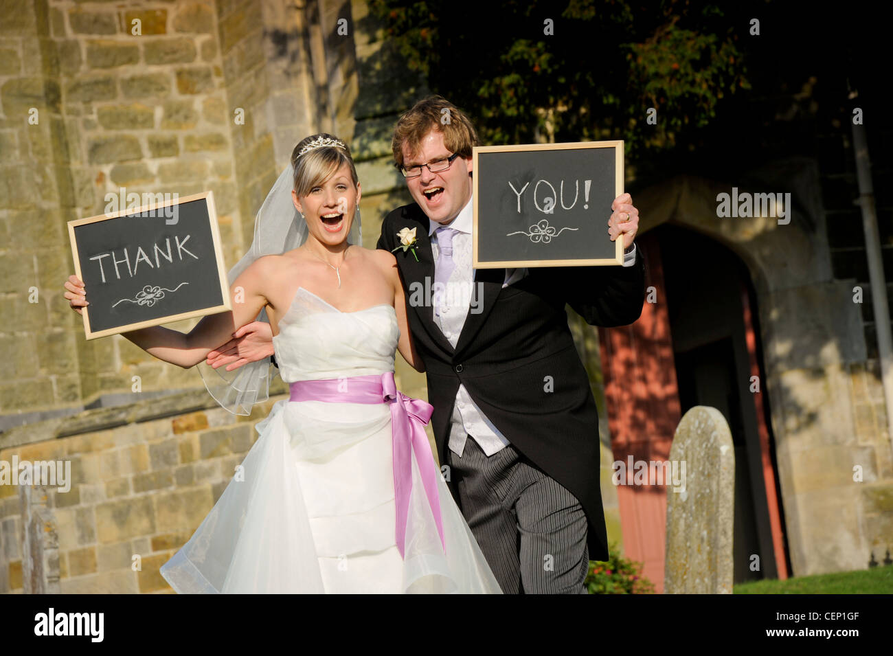 A bride and groom holding a thank you message written on blackboards ...