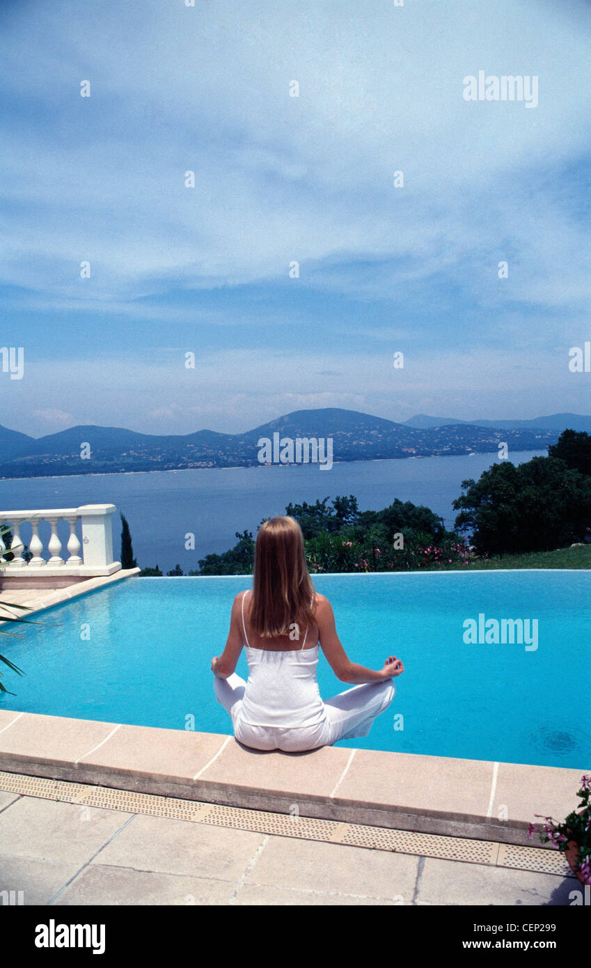 Female sitting by pool in yoga meditation pose Stock Photo - Alamy