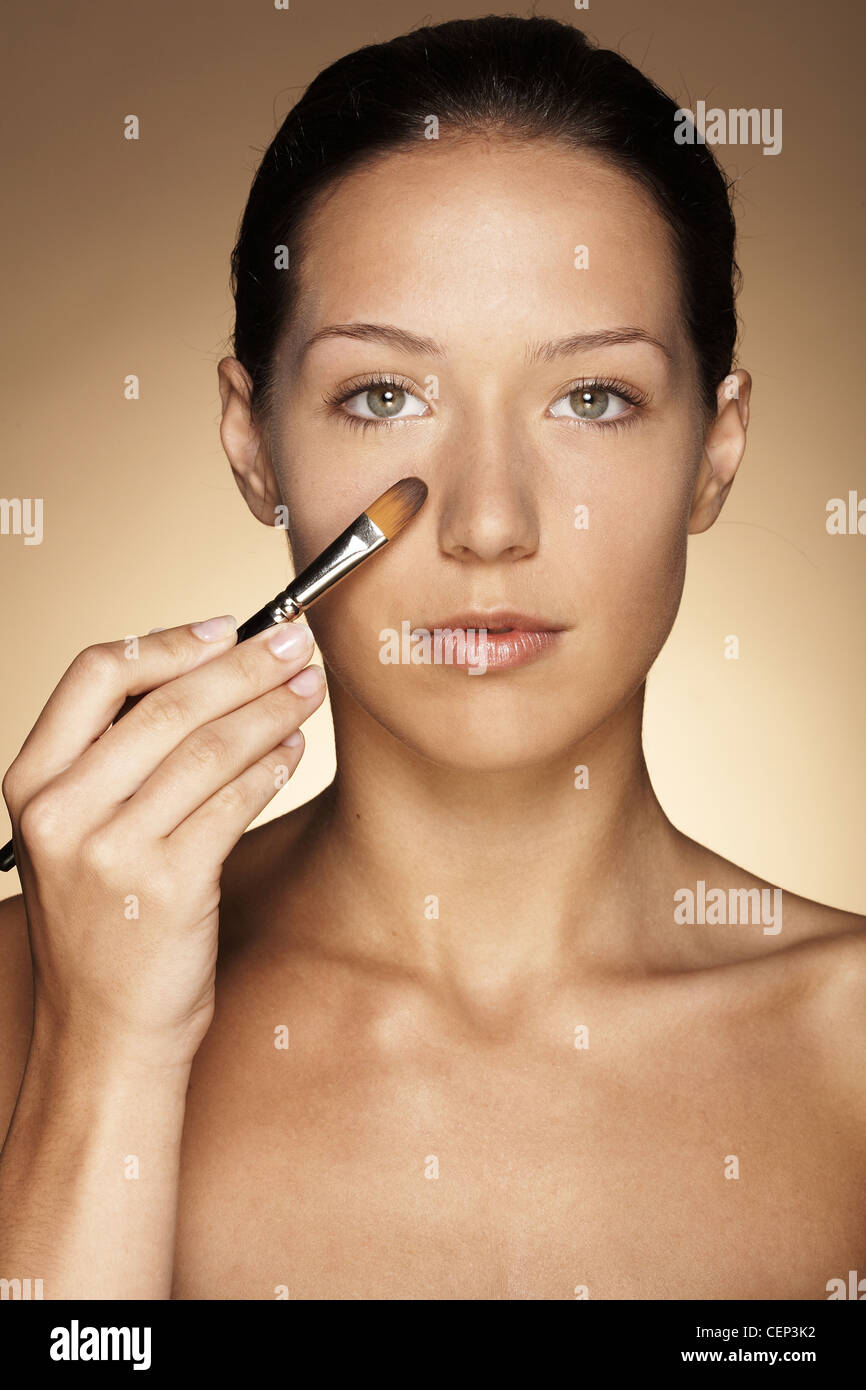 Female applying foundation to her cheek with a brush Stock Photo - Alamy