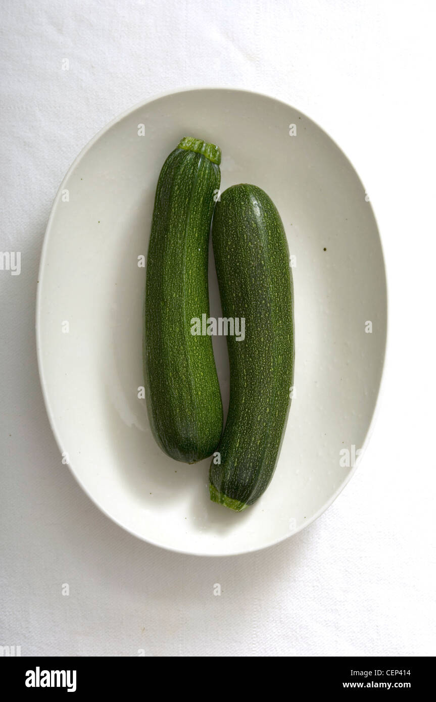 Two courgettes, on a white plate on a white background Stock Photo - Alamy