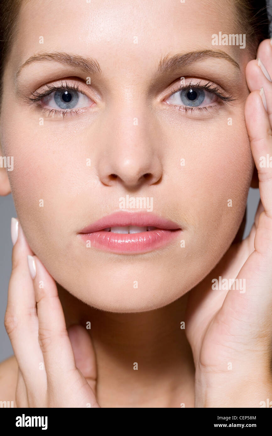 Female wearing natural make up, with her hands on the side of her face ...