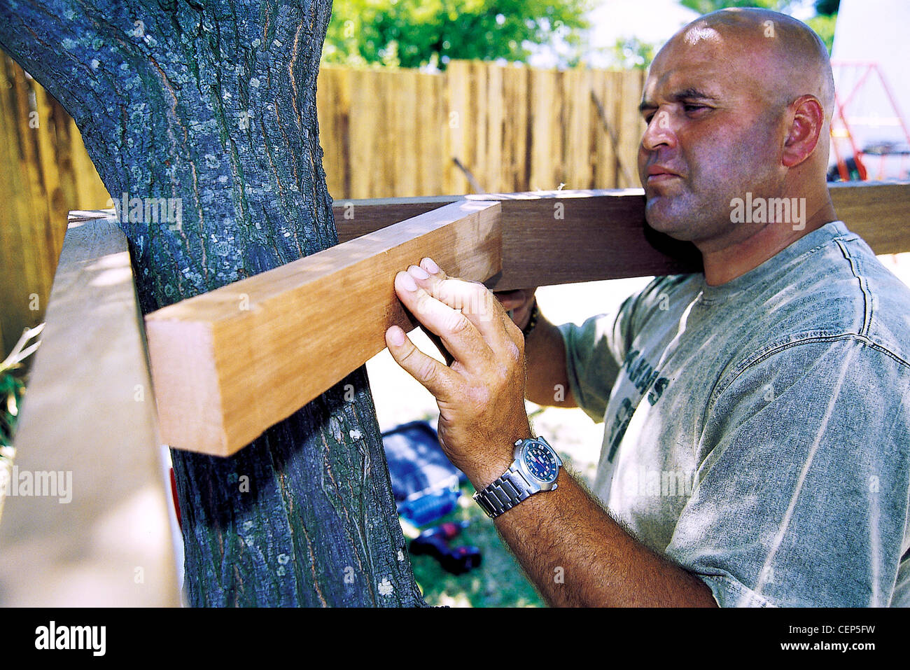FORBuild a Tree House Step Male attaching the reinforcing plank of wood ...