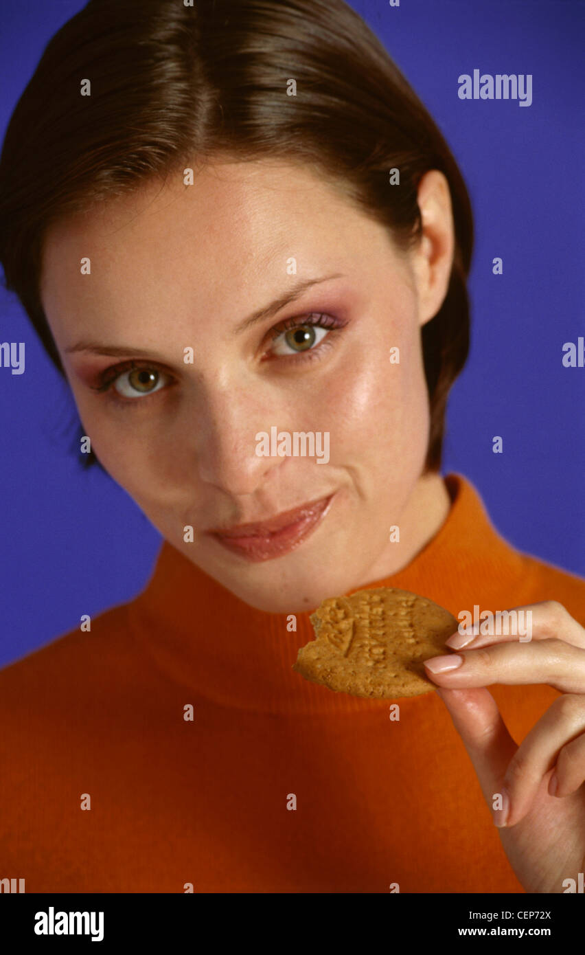 Female with short brunette hair, wearing an orange top, holding a ...