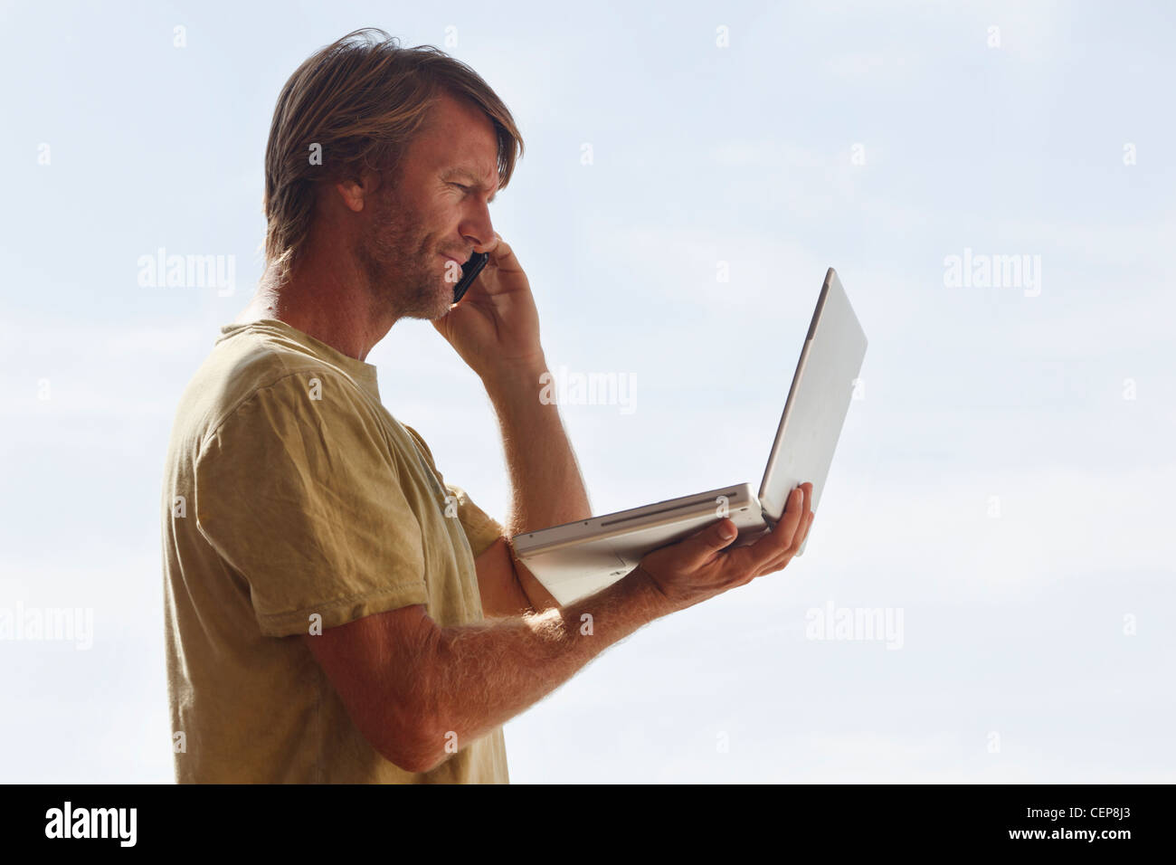 a man reading from his portable computer screen while talking on the ...