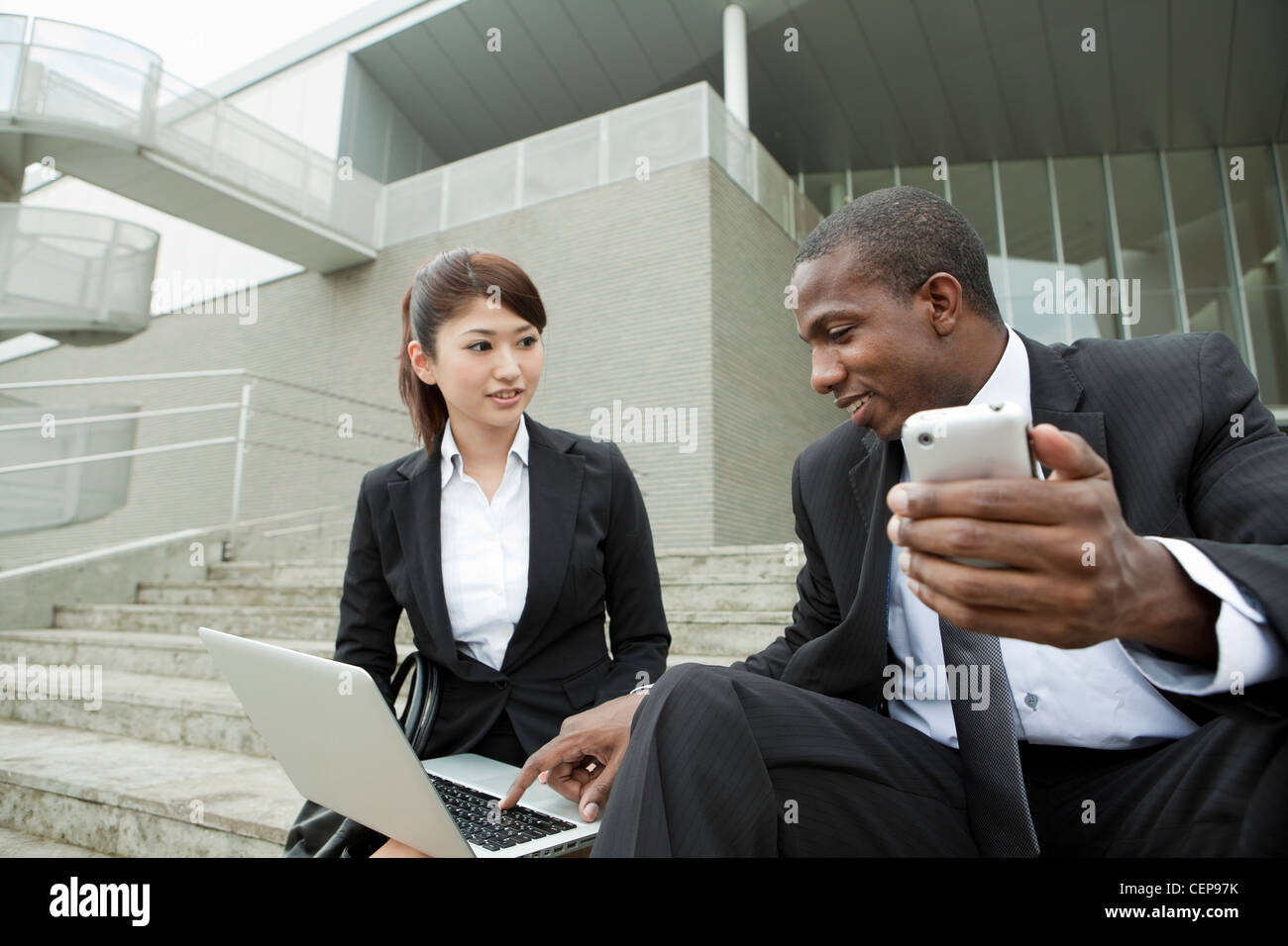 Businessman and businesswoman talking on steps Stock Photo - Alamy