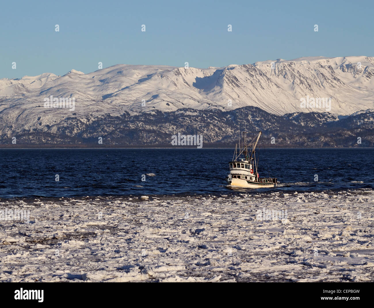 Trawler fishing boat moving through icy water in Alaska on a sunny day ...