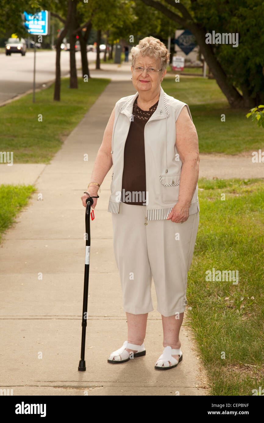 a senior woman standing with her cane on the sidewalk; edmonton ...