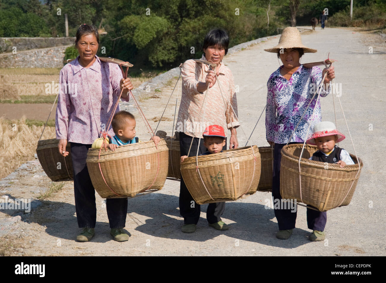 Three People Carrying Baskets With One Child In Each Stock Photo - Alamy