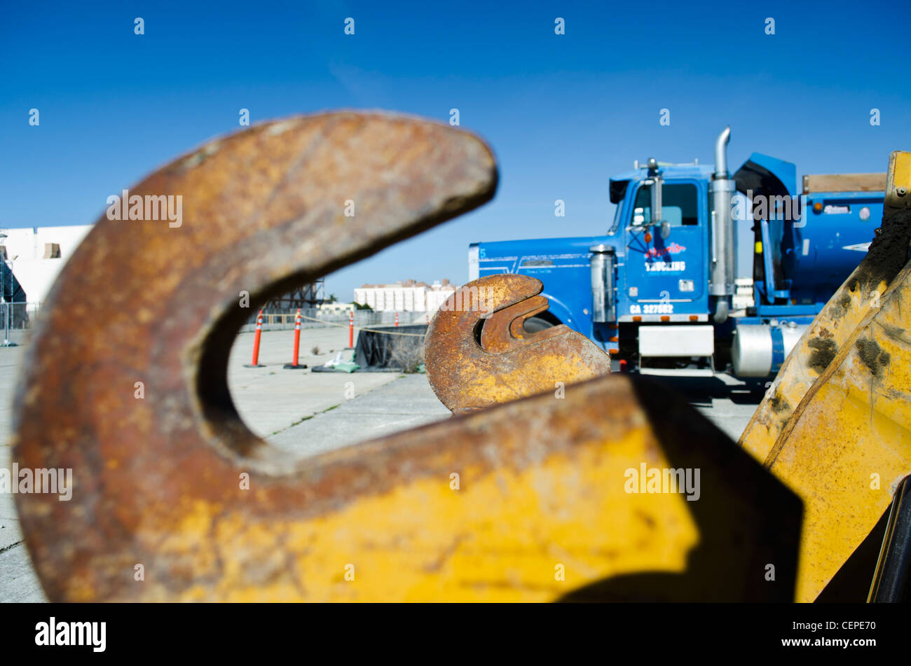 Top of a yellow loader bucket with a blue dump truck in the background ...
