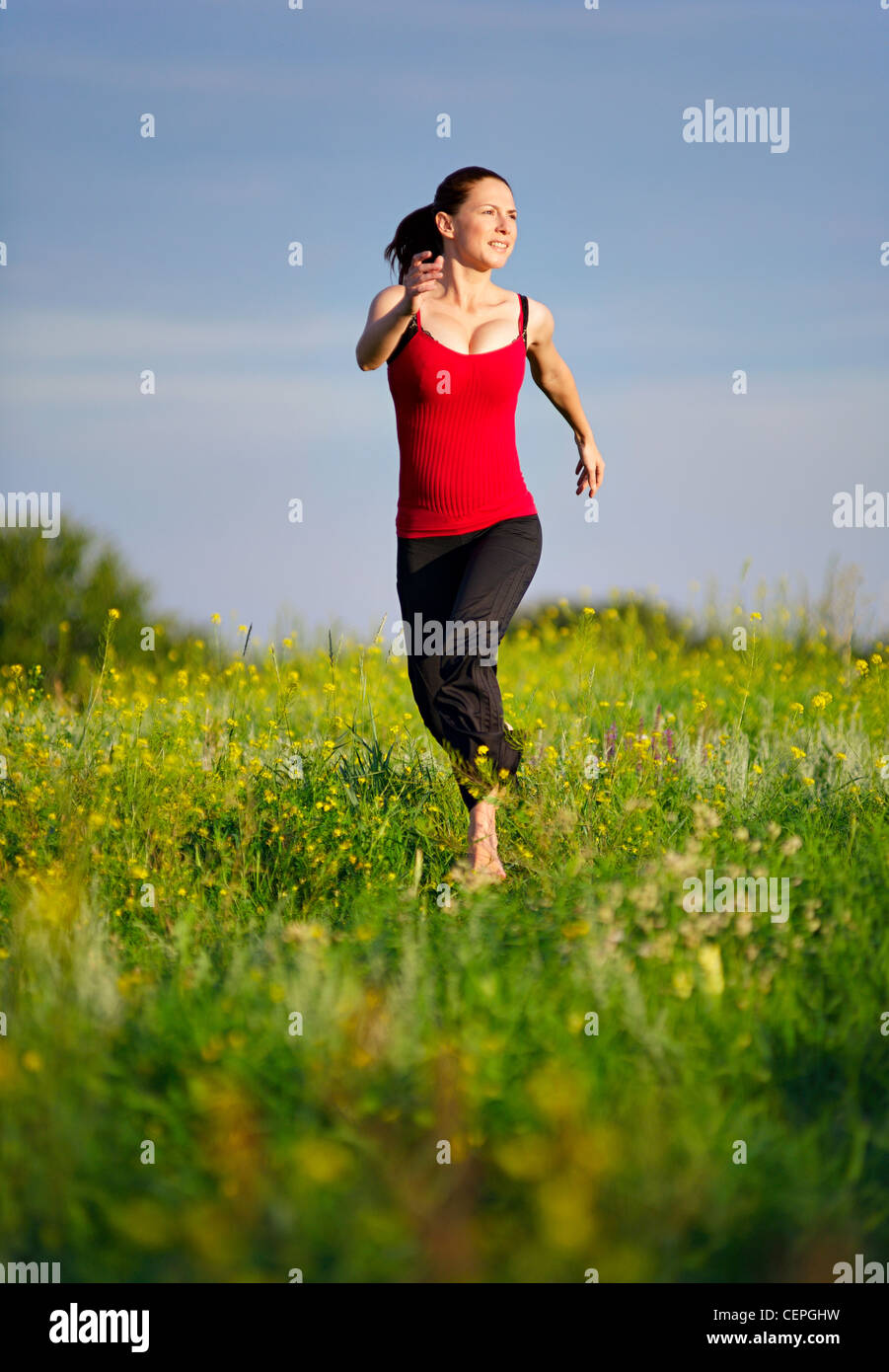 Sport woman running on a sunset field Stock Photo - Alamy