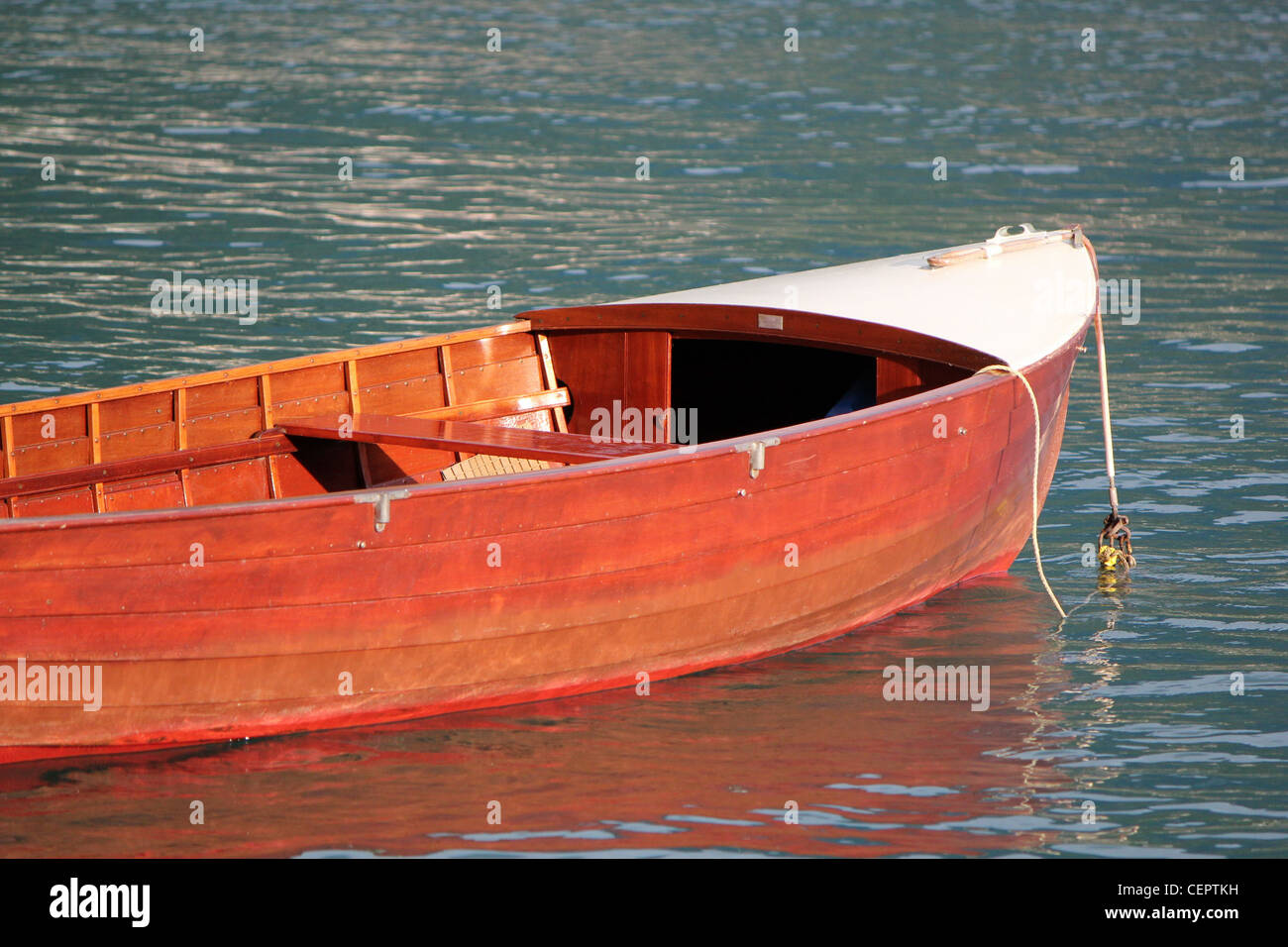 Small red wood boat floating on the water by sunset Stock Photo - Alamy