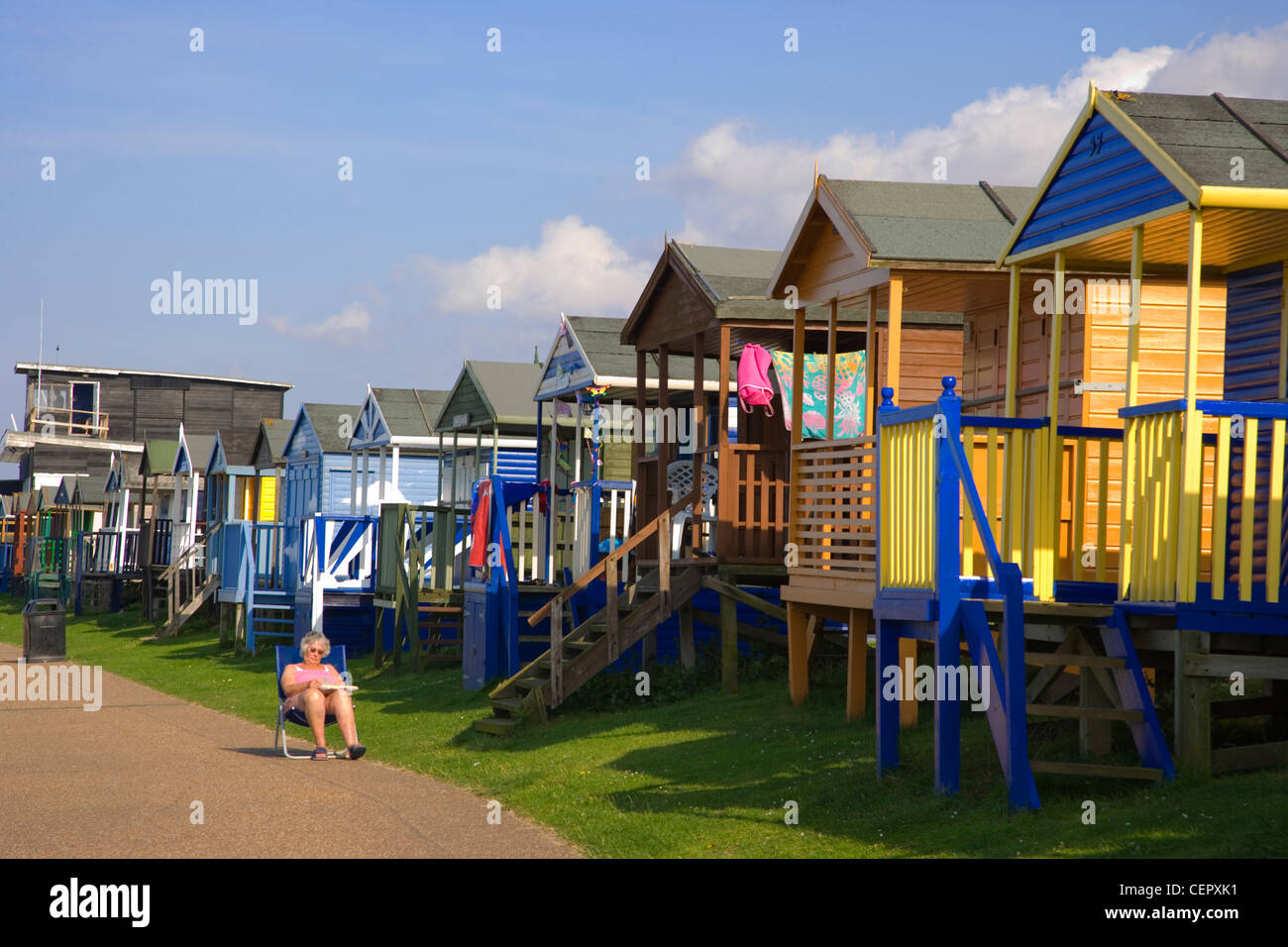 A woman relaxing in a chair outside her beach hut at Tankerton Slopes ...
