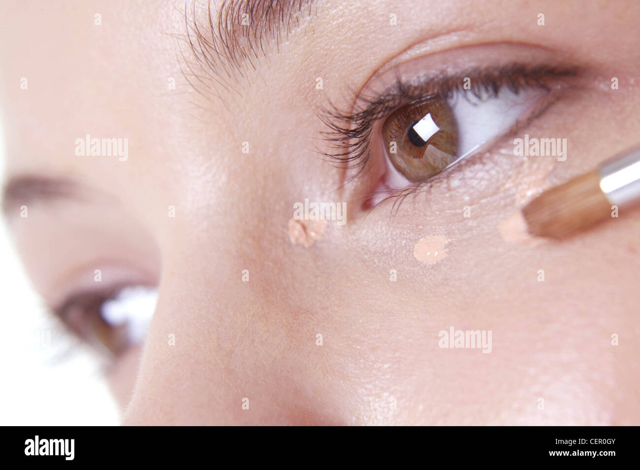 Cropped shot of female eye area applying concealer to under eye with ...