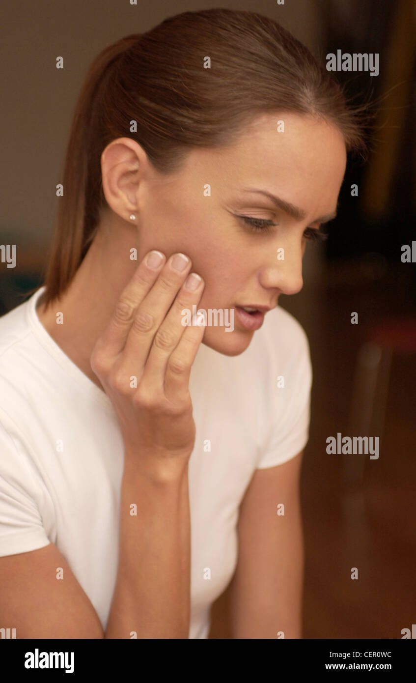 Semi profile of female with brunette hair off face wearing white t ...