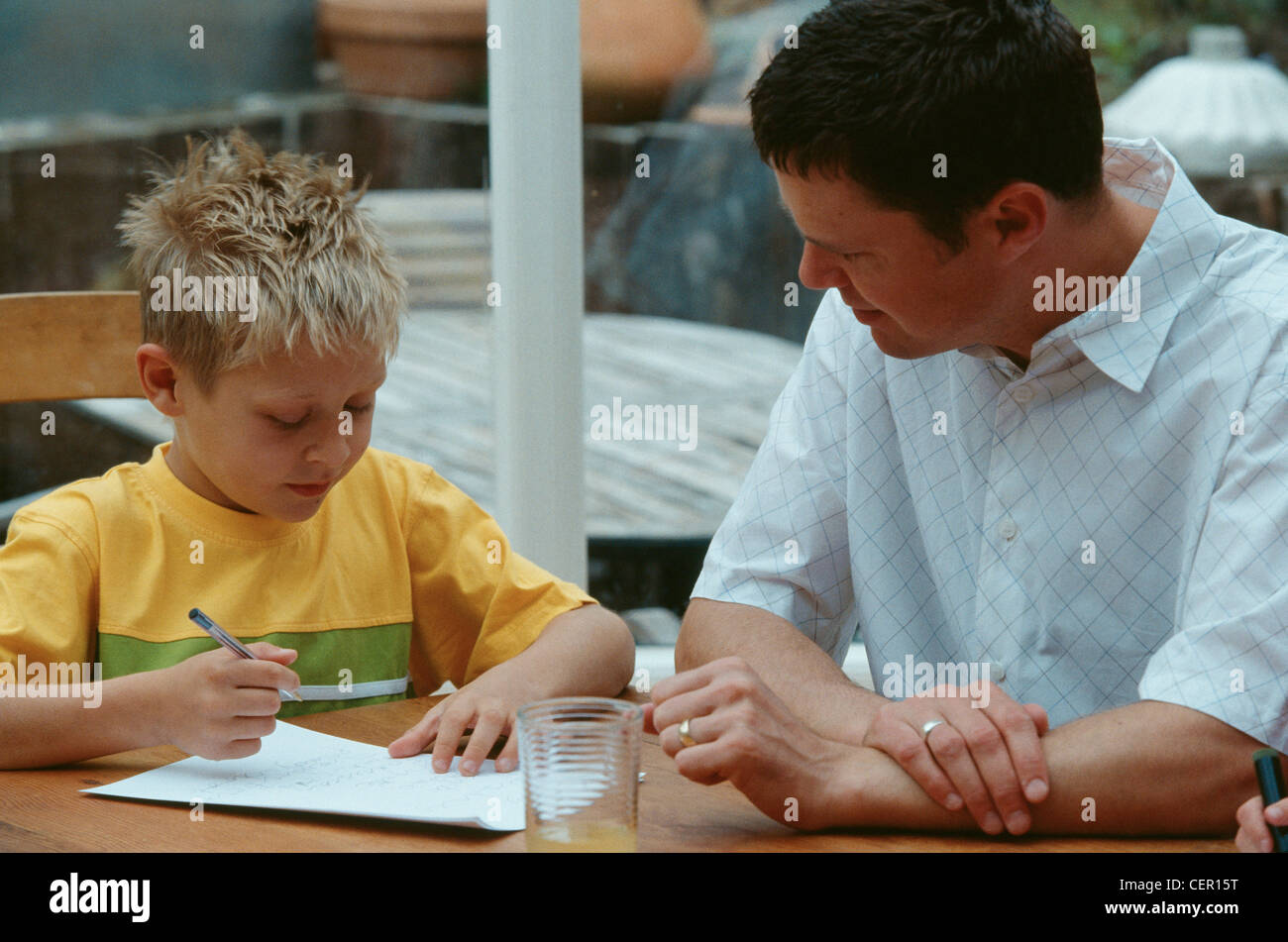 Father with short brown hair sitting at table looking over male child ...