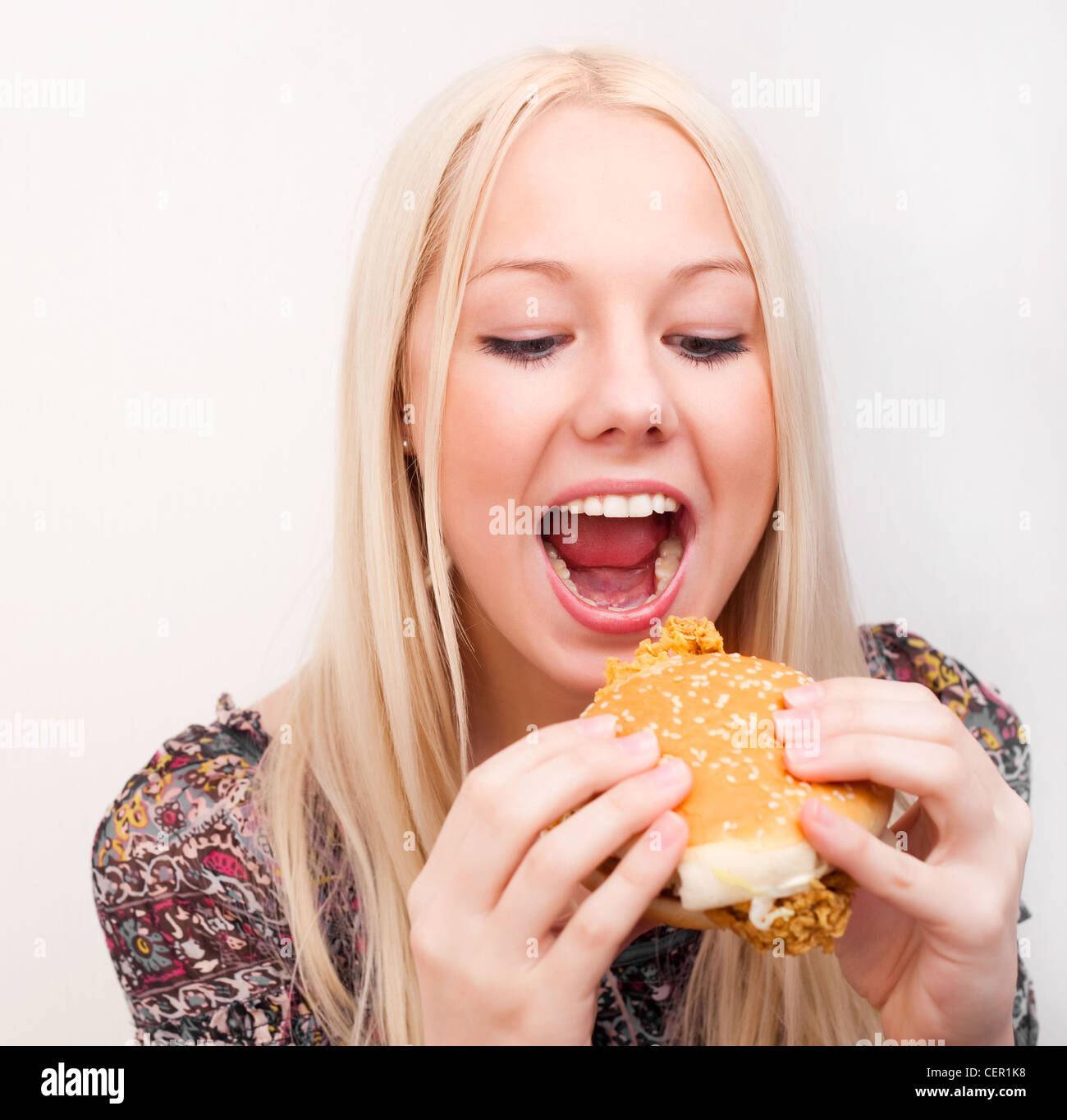 beautiful woman eating a burger, isolated against white background ...