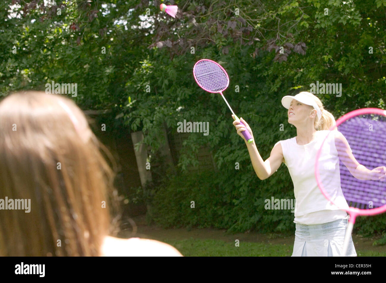 Two females playing badminton, back view of female in foreground long ...