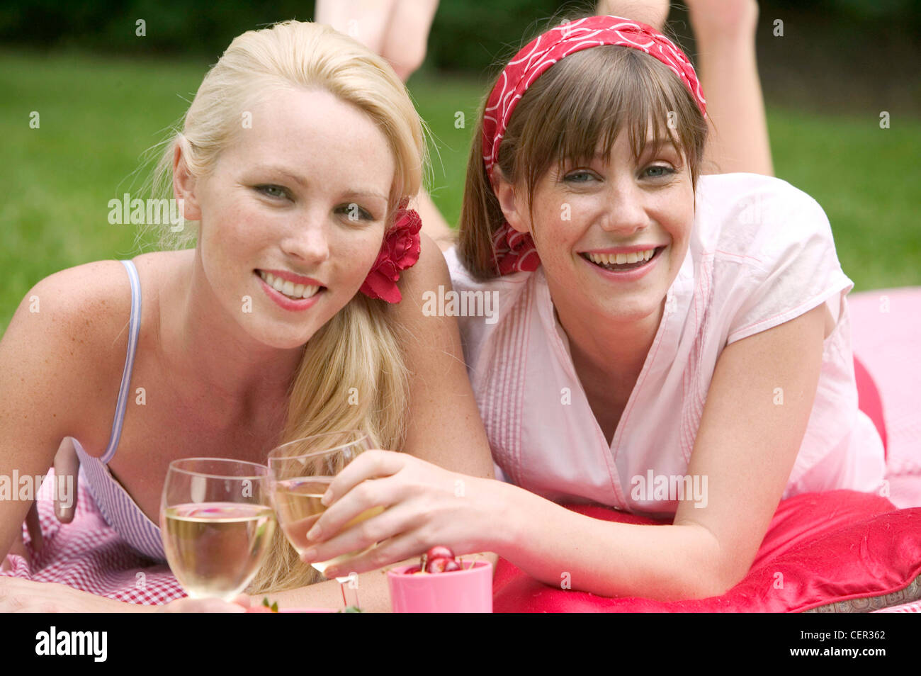 Two females lying on front propped up on elbows legs crossed at ankles ...