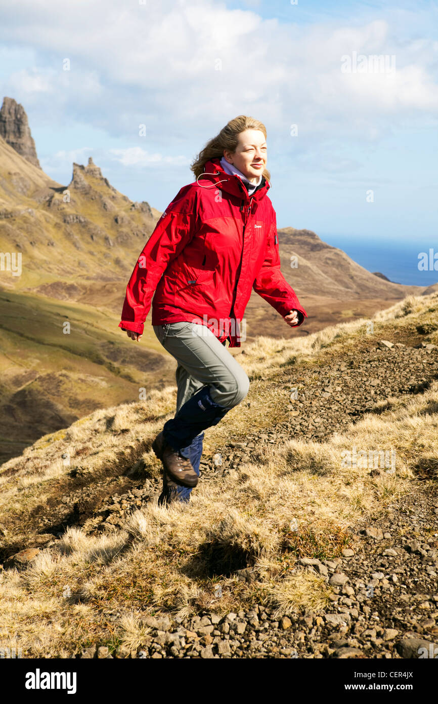 A female walker wearing a red waterproof climbing up a path over the ...
