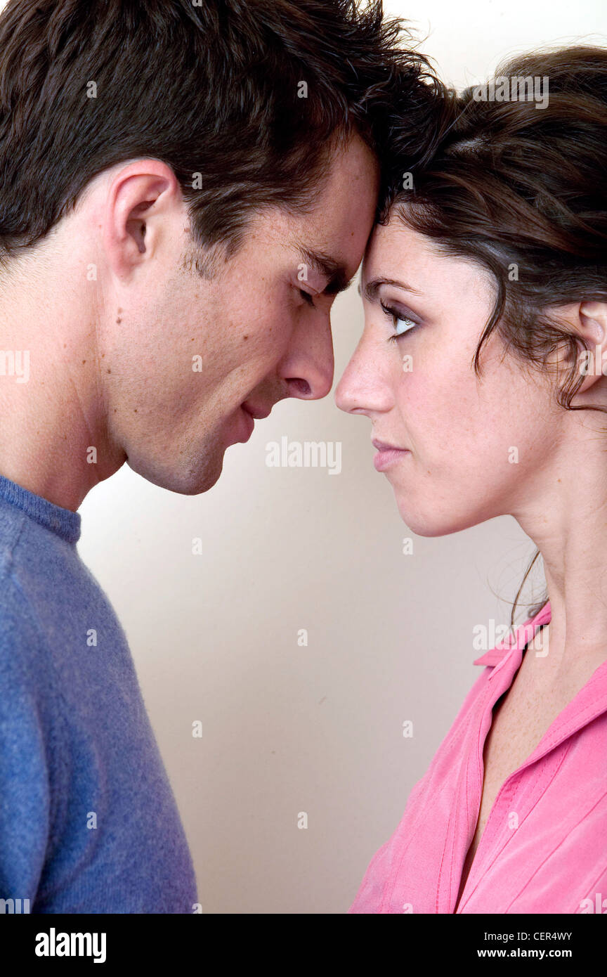 Profile of couple standing heads together touching noses, male on left ...