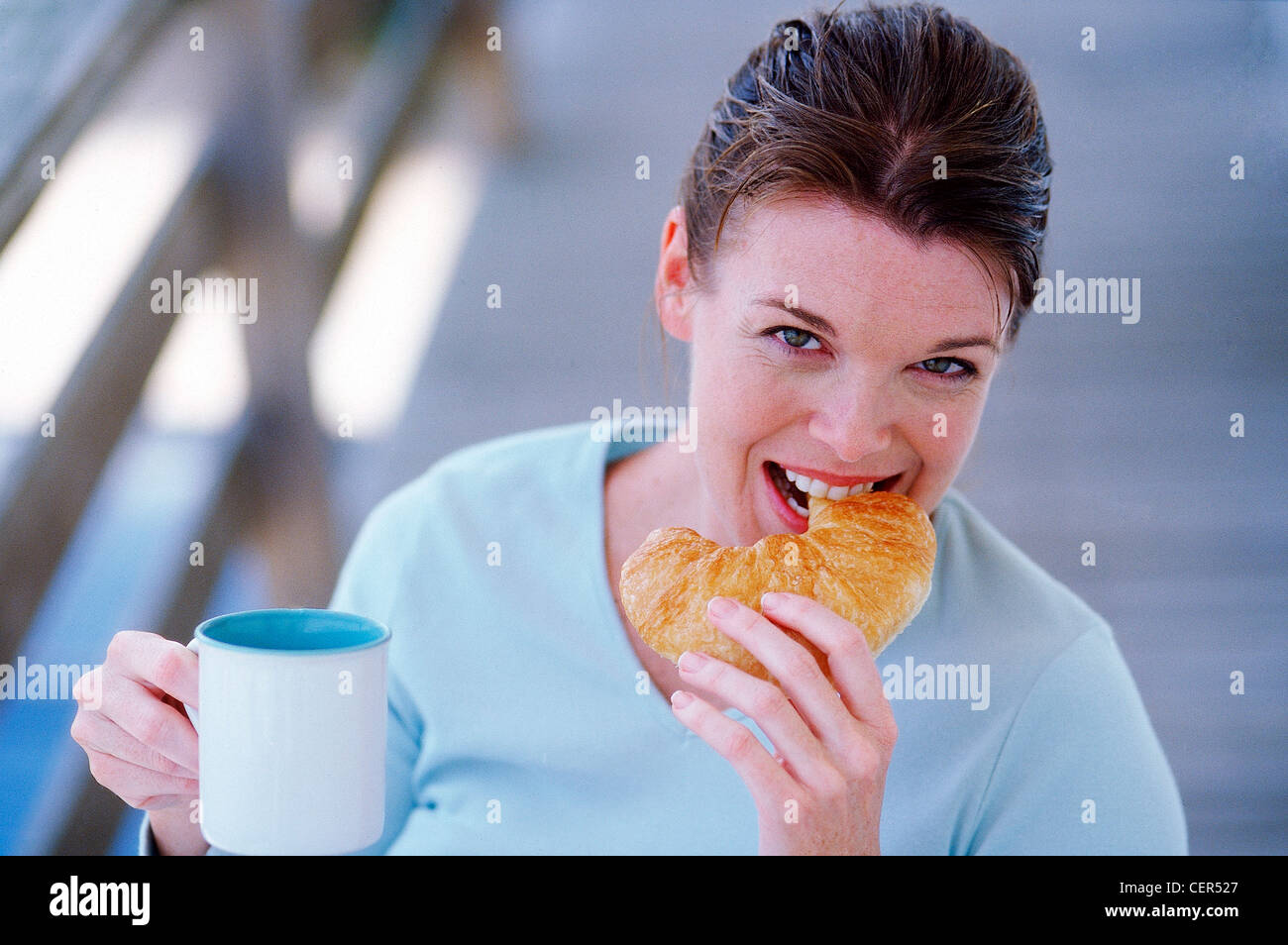 Female wet brunette hair off face wearing pale blue top holding mug ...