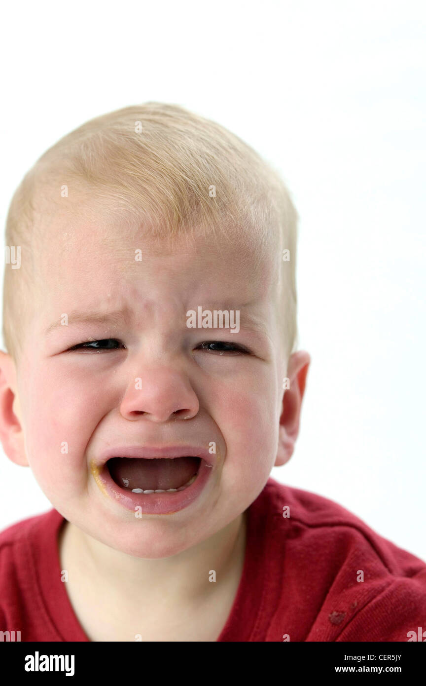 Male baby wearing red top, crying looking to camera with mouth wide ...