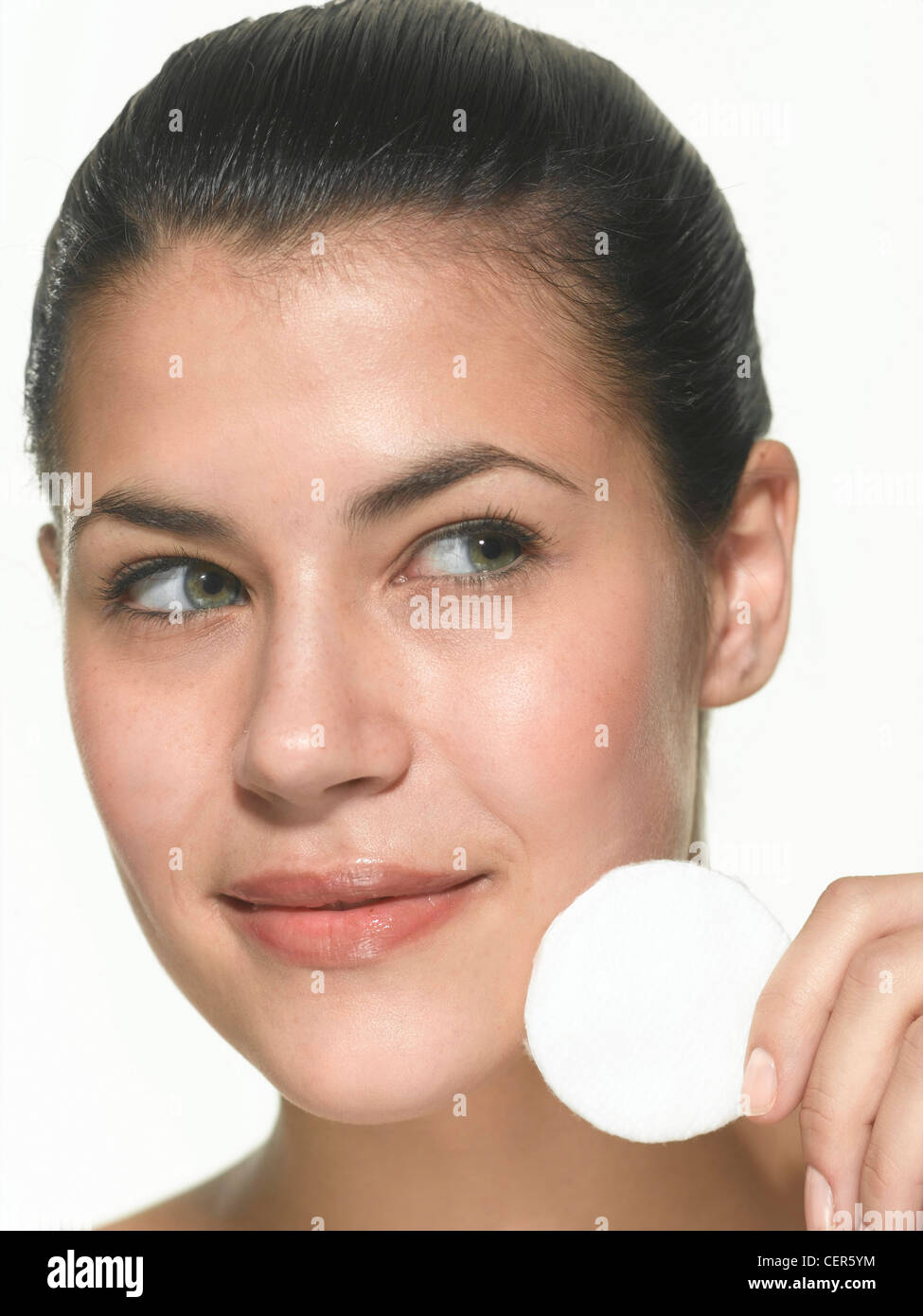 Female with brunette hair off face holding cotton wool pad to face ...
