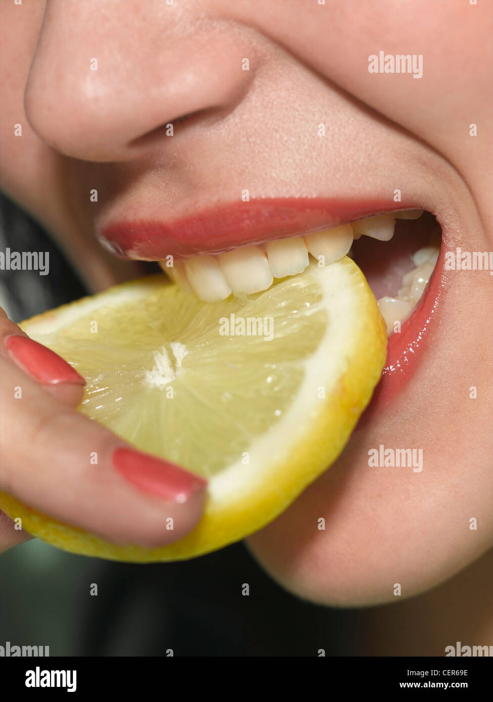 Cropped lower face of Female biting slice of lemon Stock Photo - Alamy