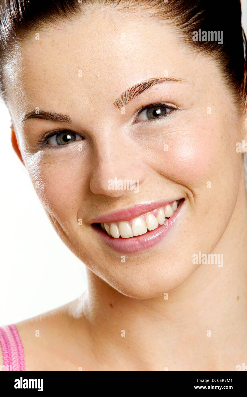 Female with brunette hair off face looking to camera smiling, against ...