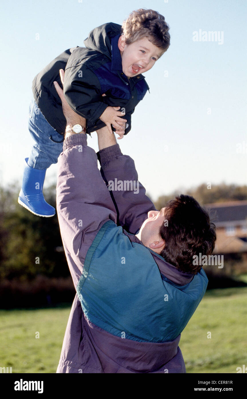 Back view of male lifting male child up in air, child with mouth open ...