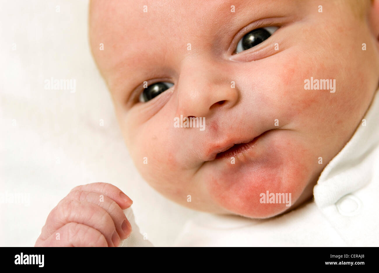 Cropped image of new born baby wearing white baby gro, looking past ...