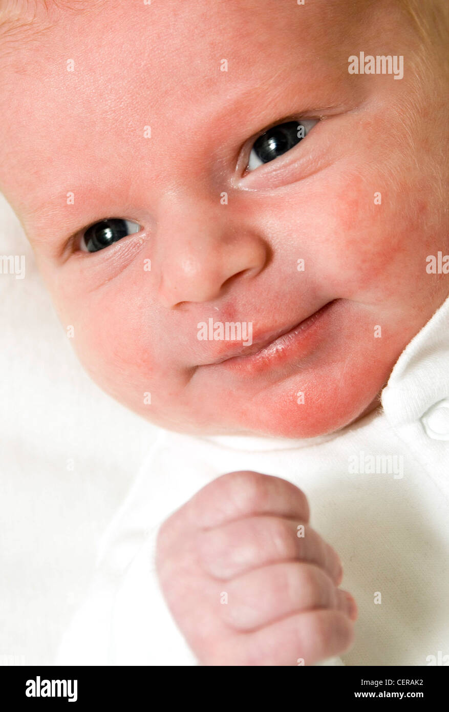 Cropped image of new born baby wearing white baby gro, looking past ...