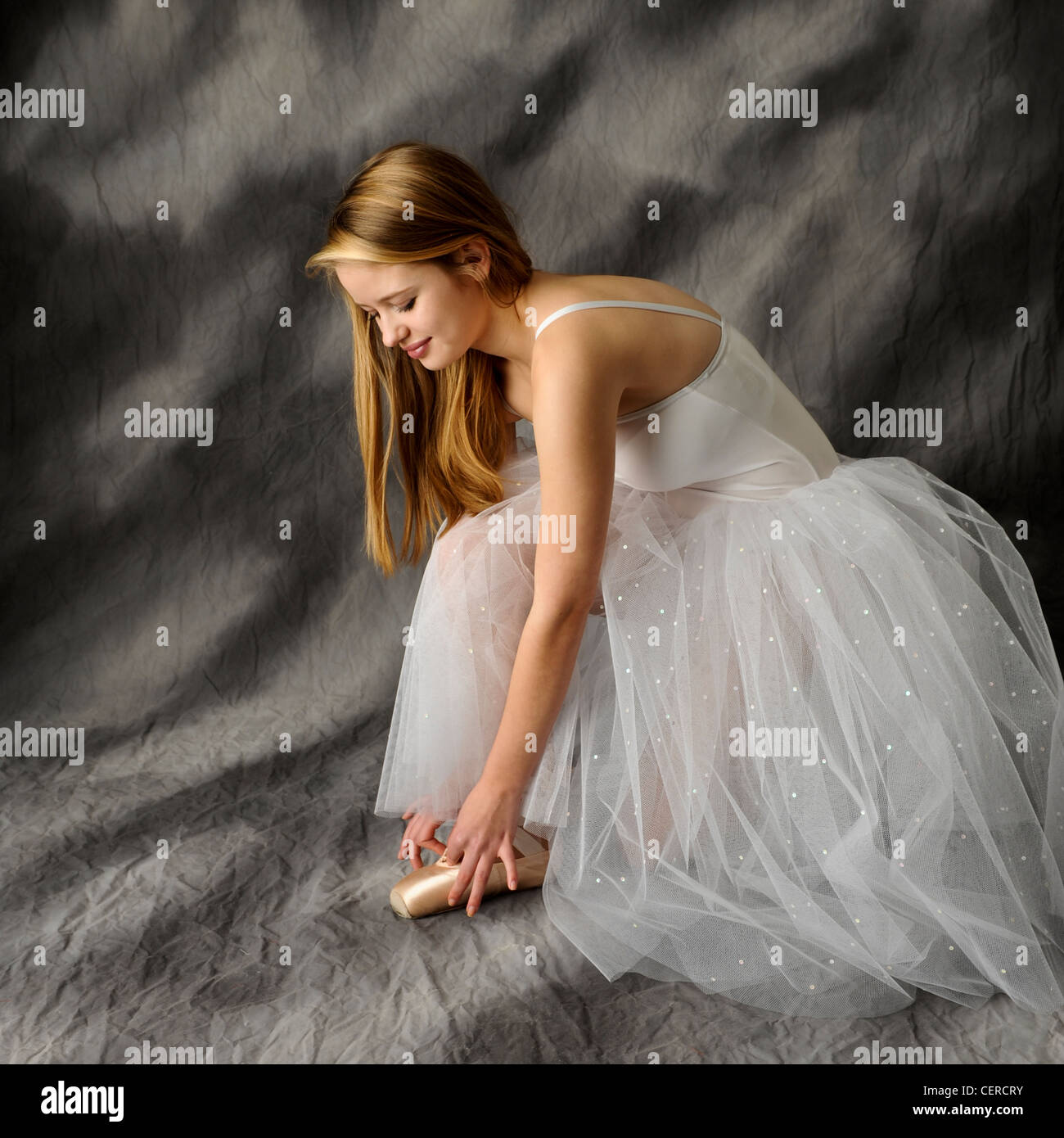 Lovely young modern ballerina tying ballet slippers and getting ready ...