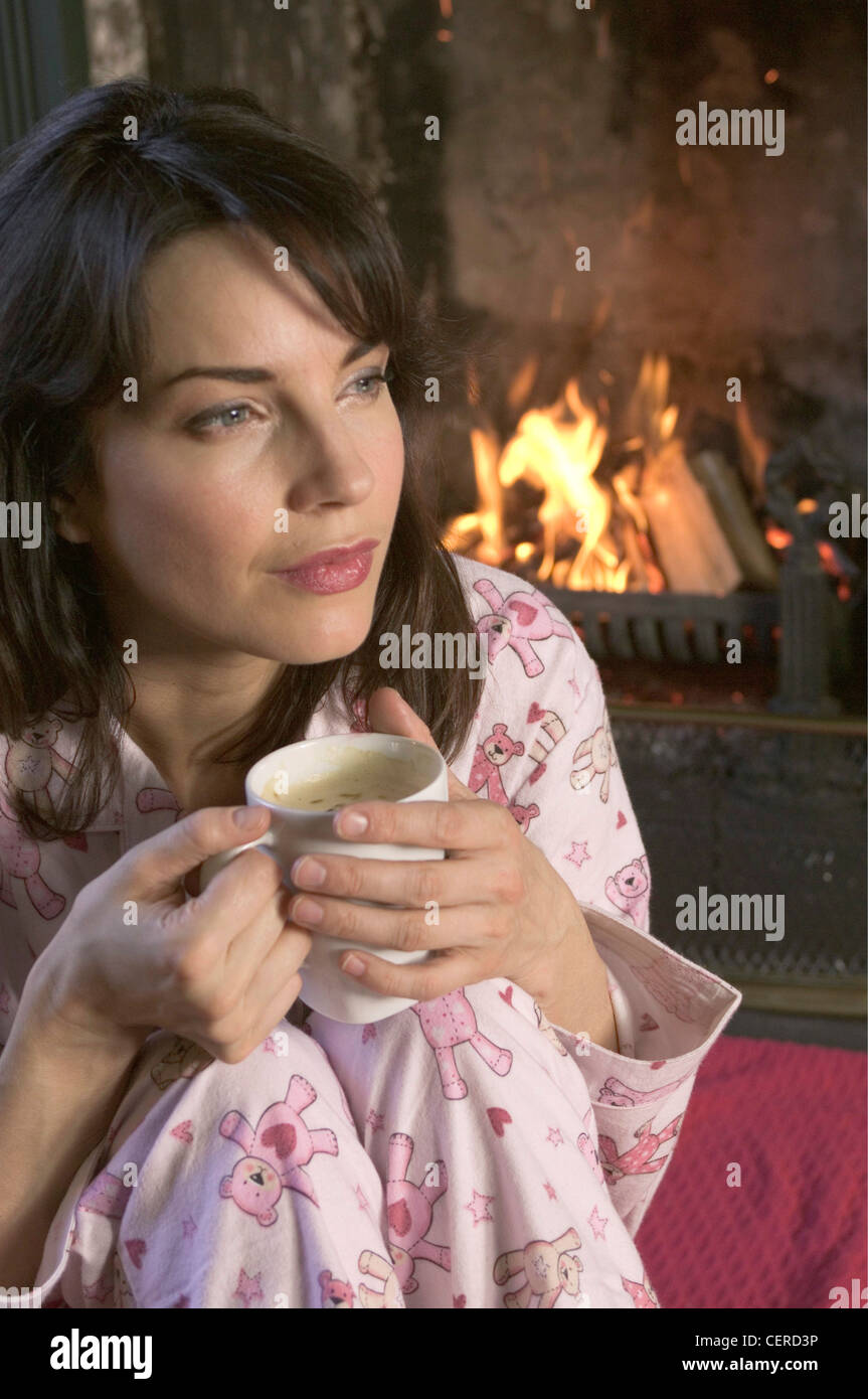 Brunette female wearing pink teddy bear print pyjamas, sitting by an ...
