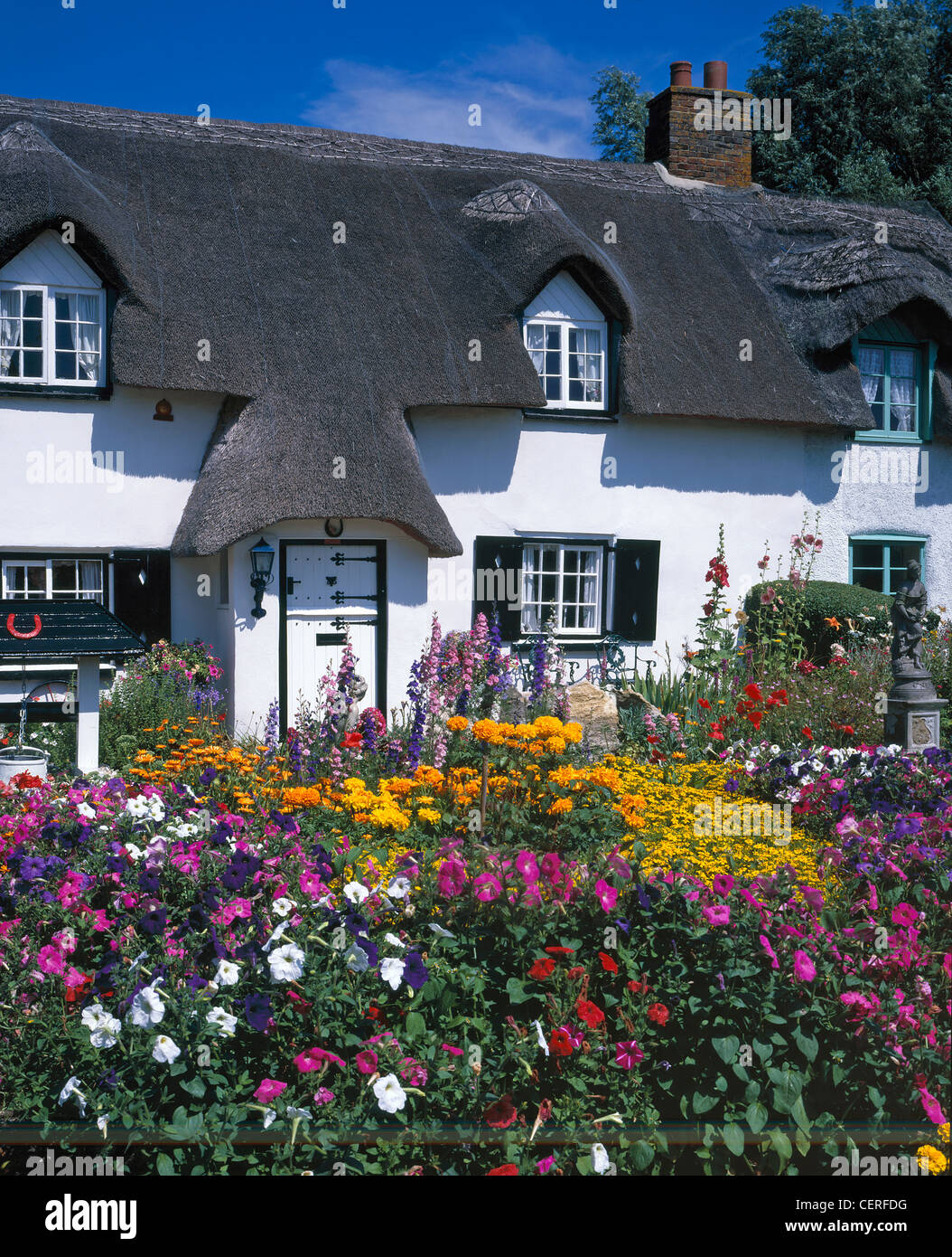 A thatched cottage with flowers in full bloom in the garden Stock Photo ...