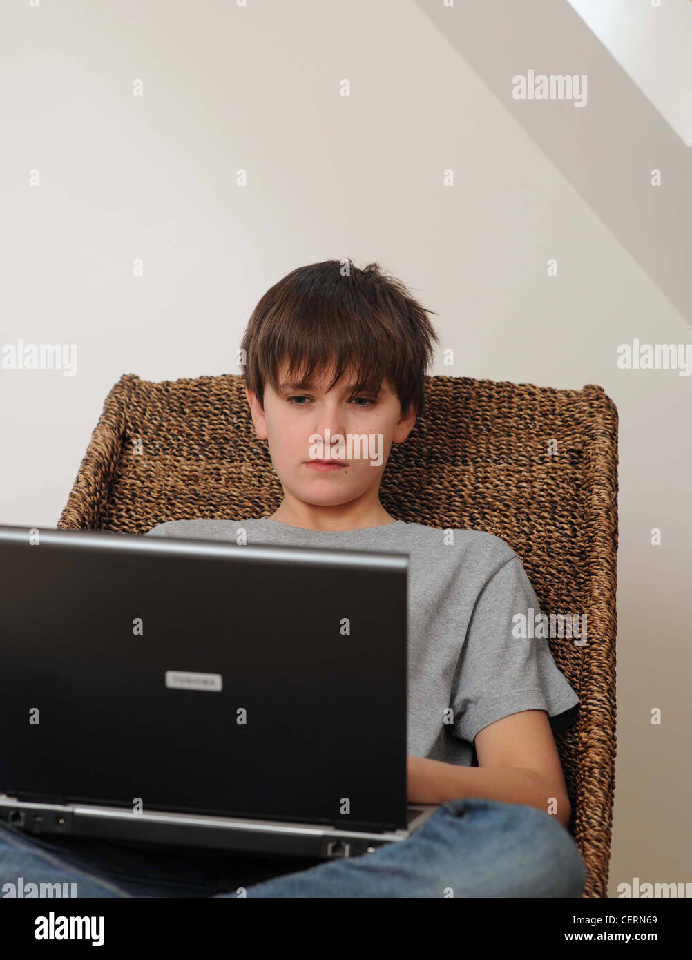 Male child sitting in chair using laptop Stock Photo - Alamy