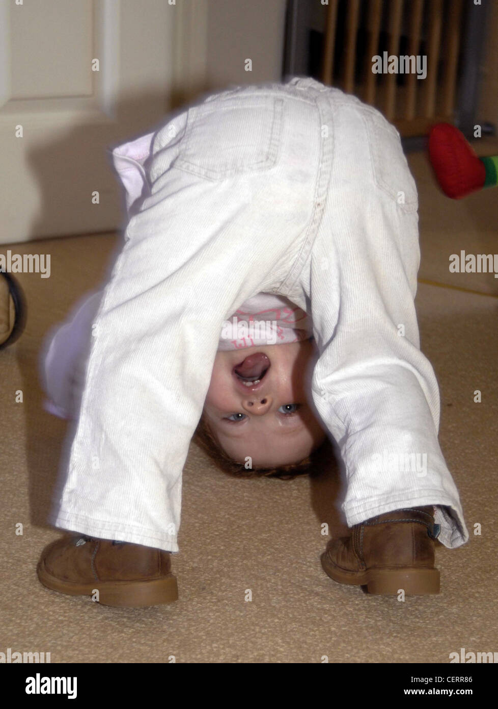 A young toddler with her head on the flolooking through her legs Stock ...