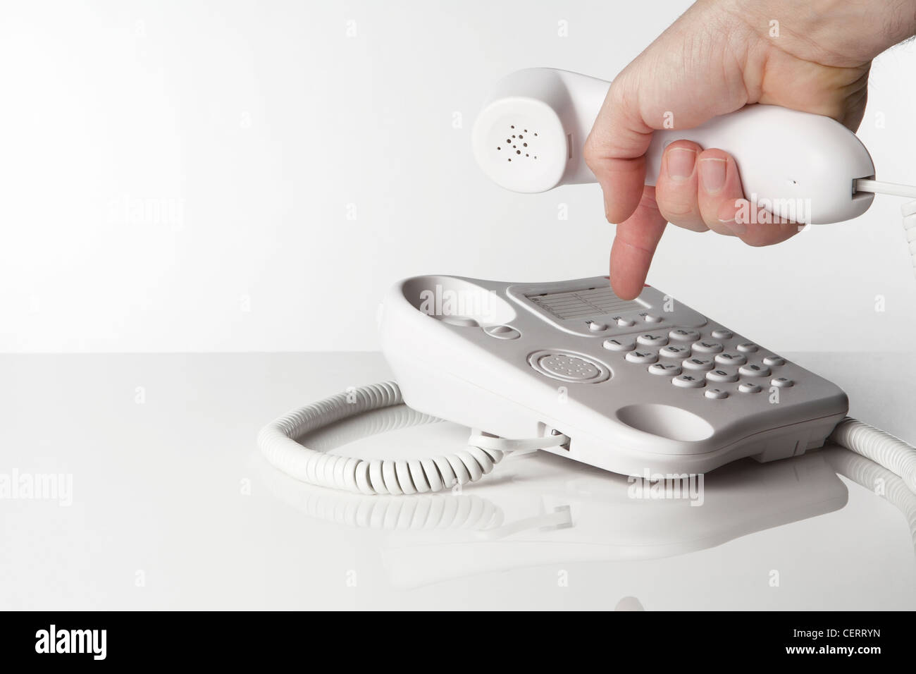 image of a telephone on a white background with a hand in the shot ...